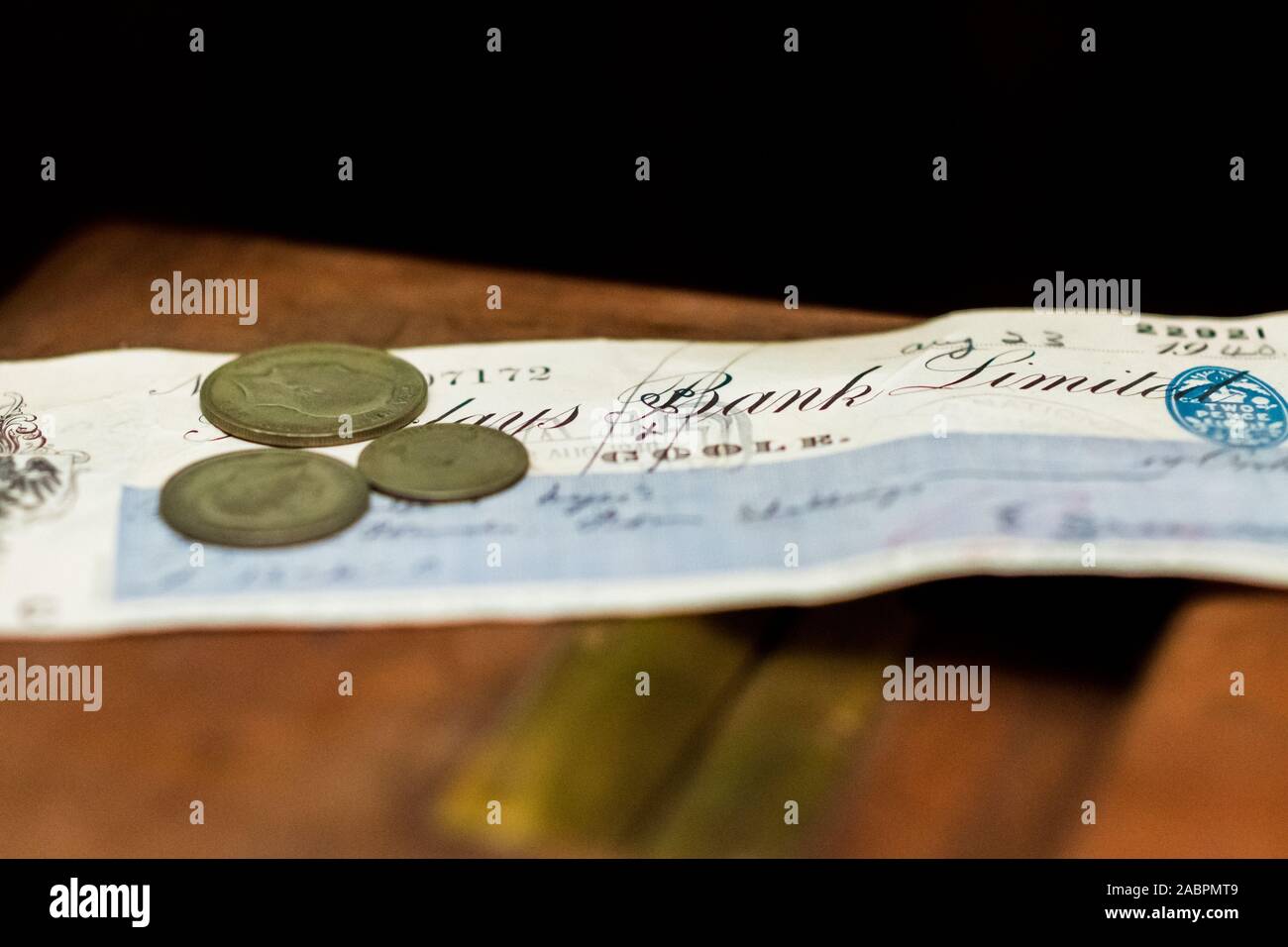 Some old british coins sit on top of a bank cheque from 1940 during ...
