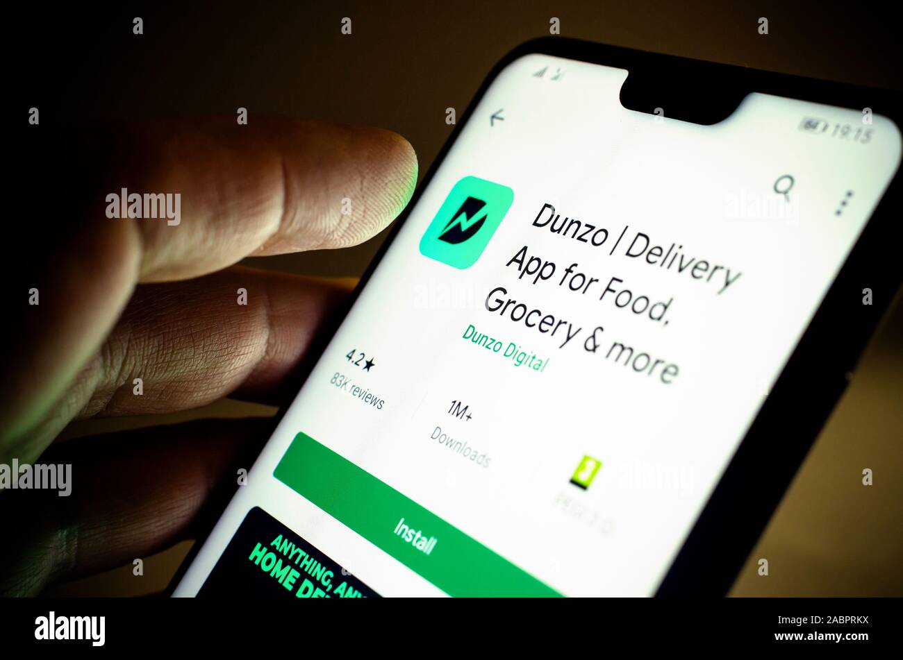 Dunzo Delivery app in Play Markert on the screen in a dark room and ...