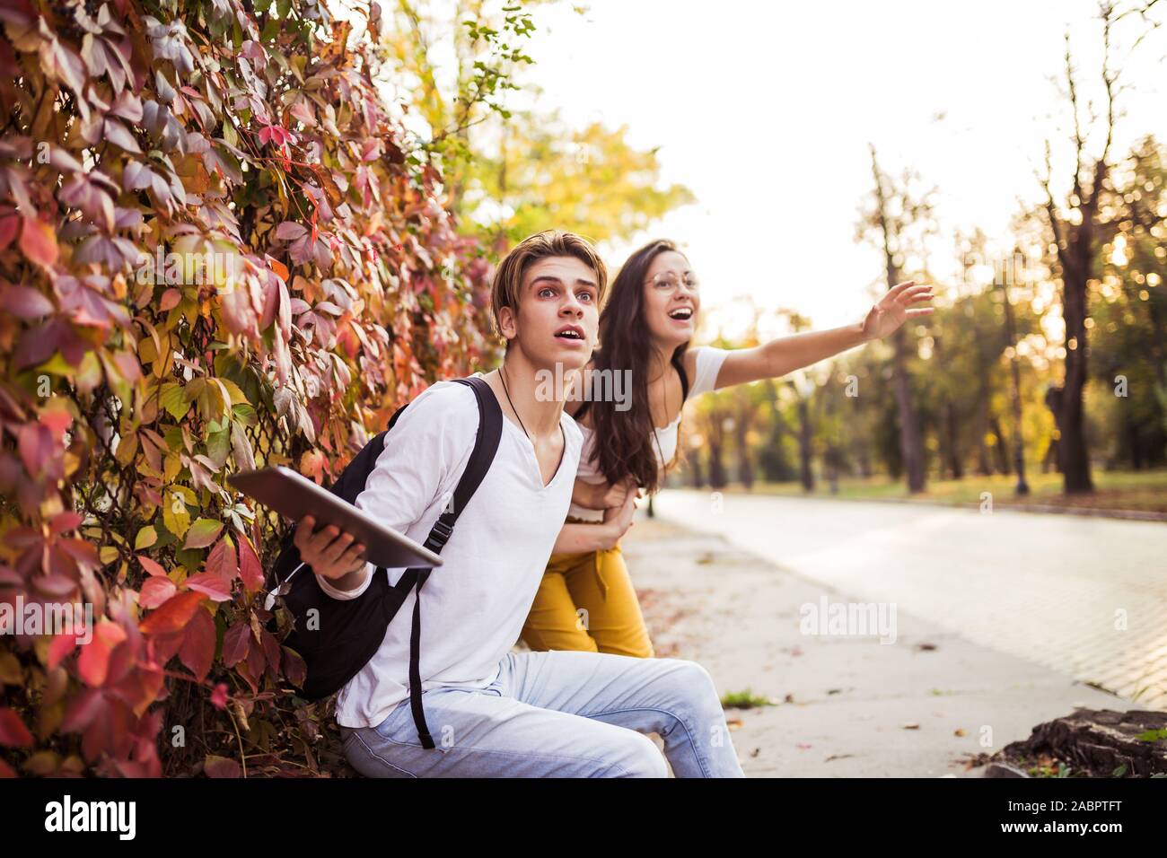 Young couple of friends stopping taxi in the street. Excited girl and ...