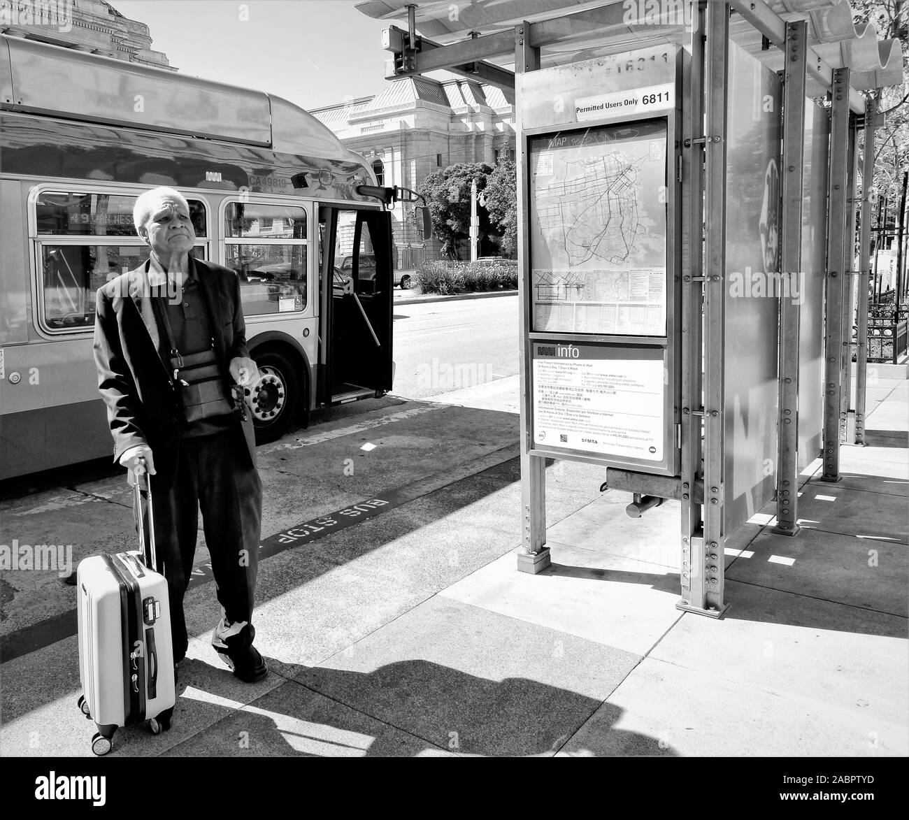 undecided old man waiting to catch a bus in San Francisco with a roller ...