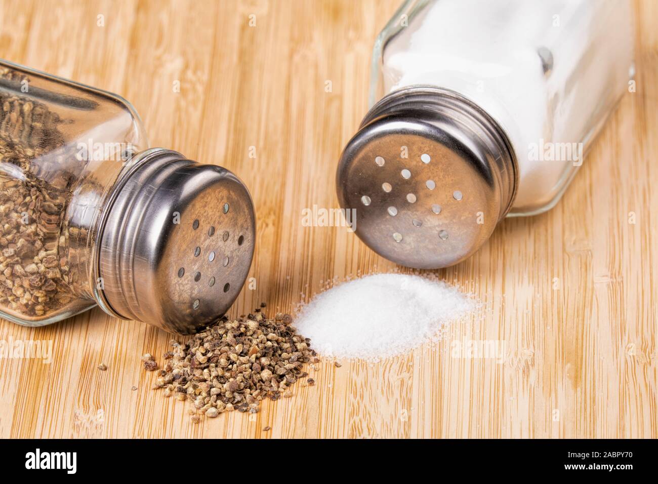 Salt and Pepper shakers with spilled salt and peeper on a wooden ...