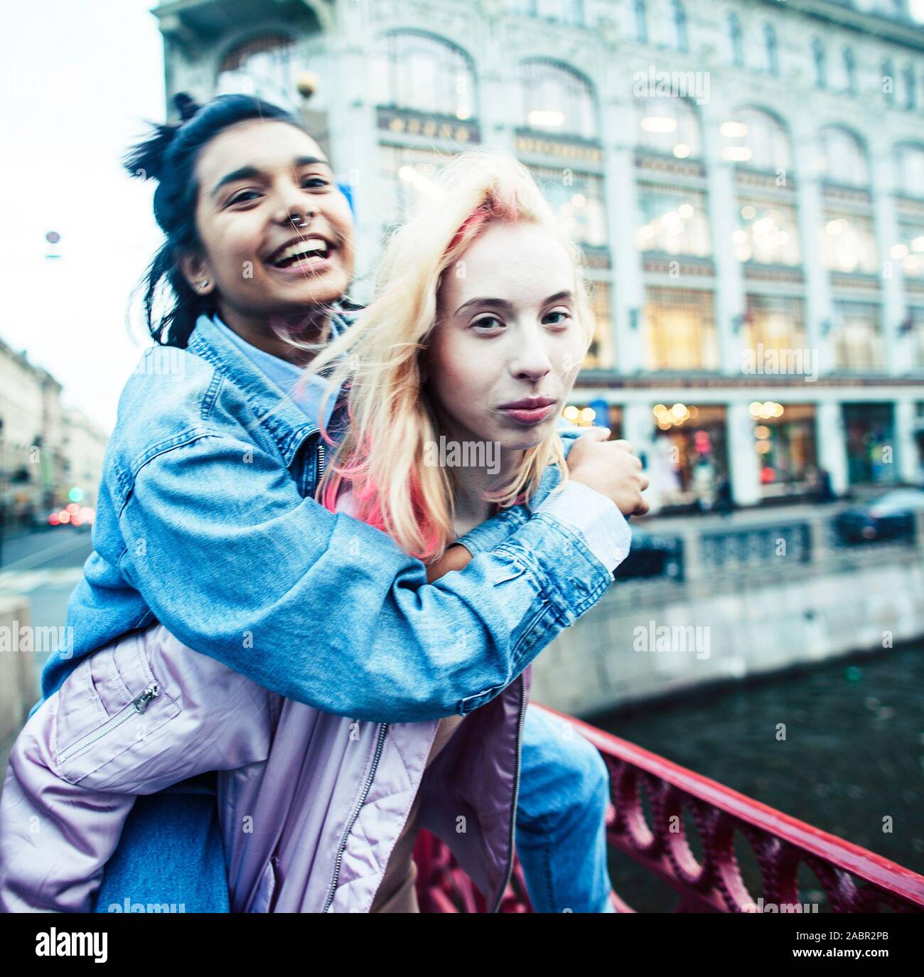 Two teenage girls infront of university building smiling, having fun ...