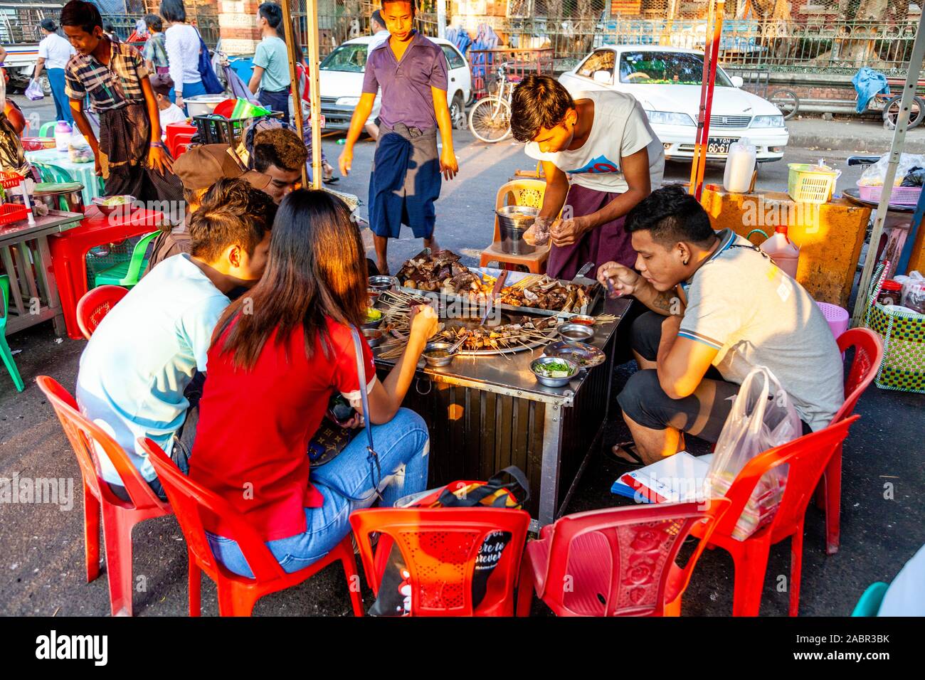 A Group Of Young People Eating Street Food From A Stall In Downtown ...