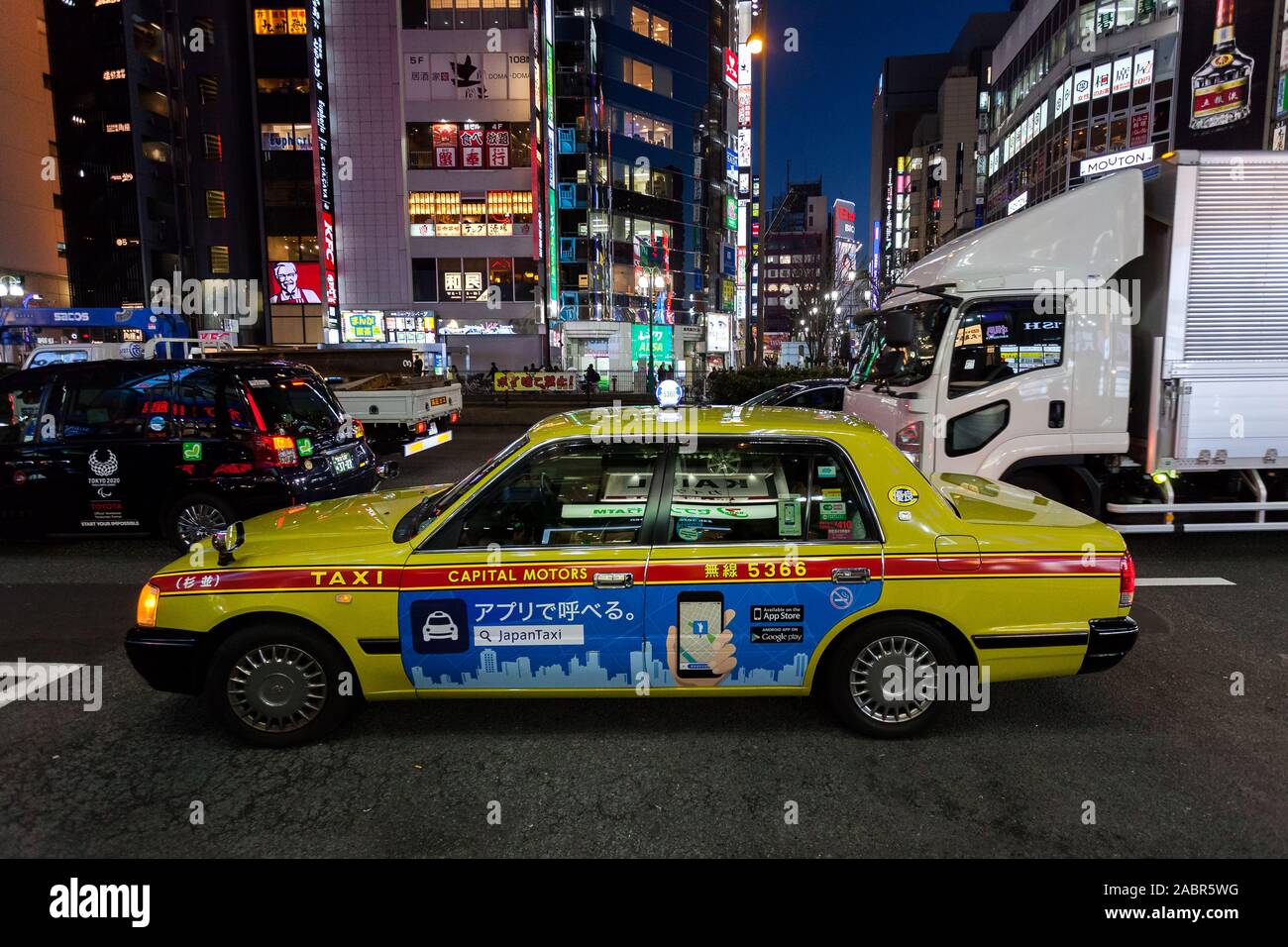 A Japanese taxi (yellow cab) in a street with other traffic in Shinjuku ...