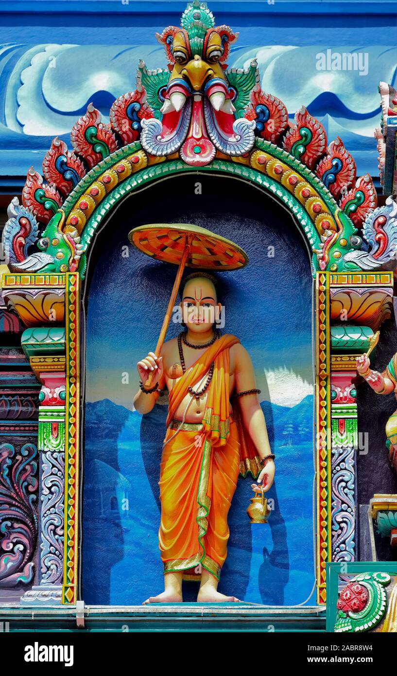 Colourful Hindu deity statue in orange robe and carrying umbrella on ...