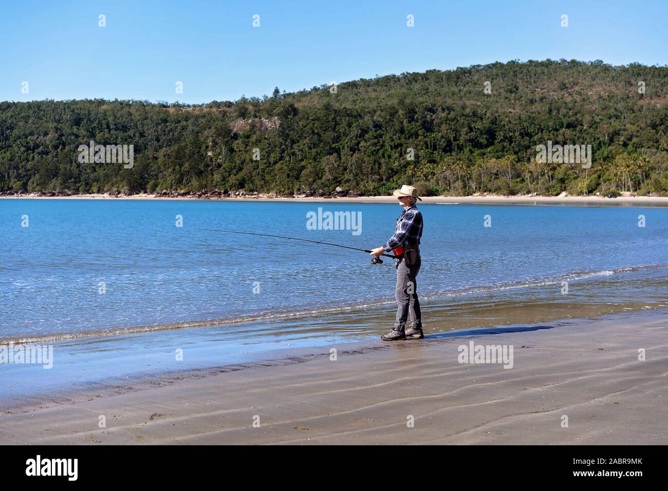 Senior male retiree fishing on the beach with his rod and reel ...