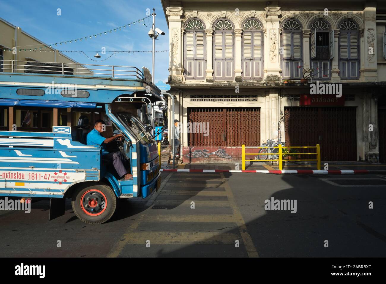 An old-style local bus (songthaew) passes a Sino-Portuguese-style house ...