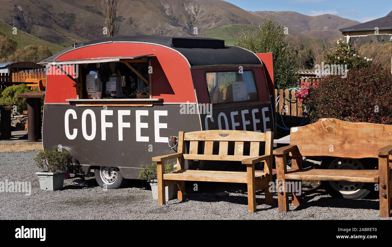 An old wooden red and brown coffee caravan on the side of the road ...