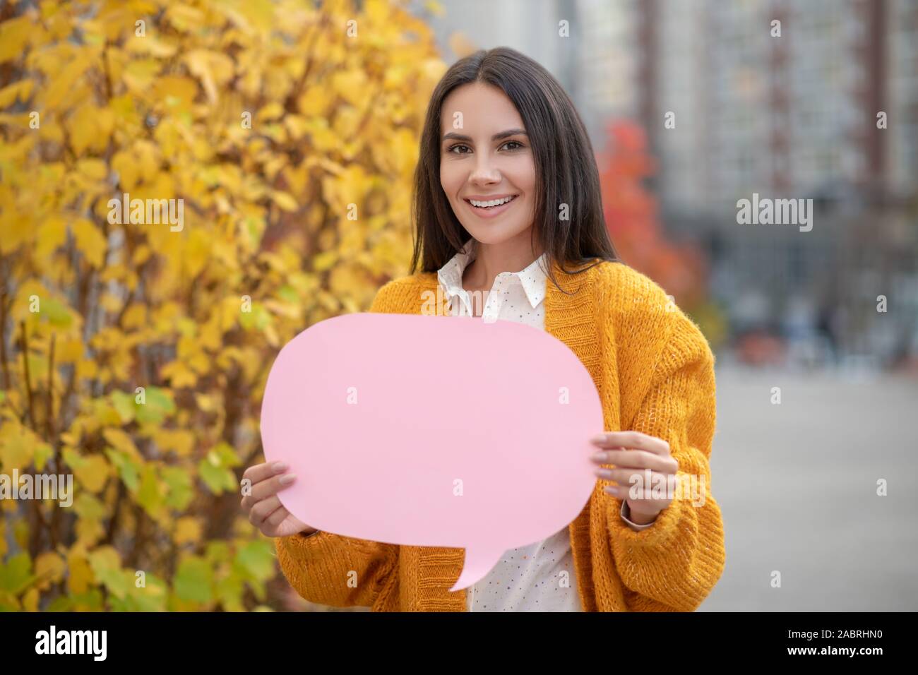 Showing thoughts. Nice dark haired woman standing with a sign while ...