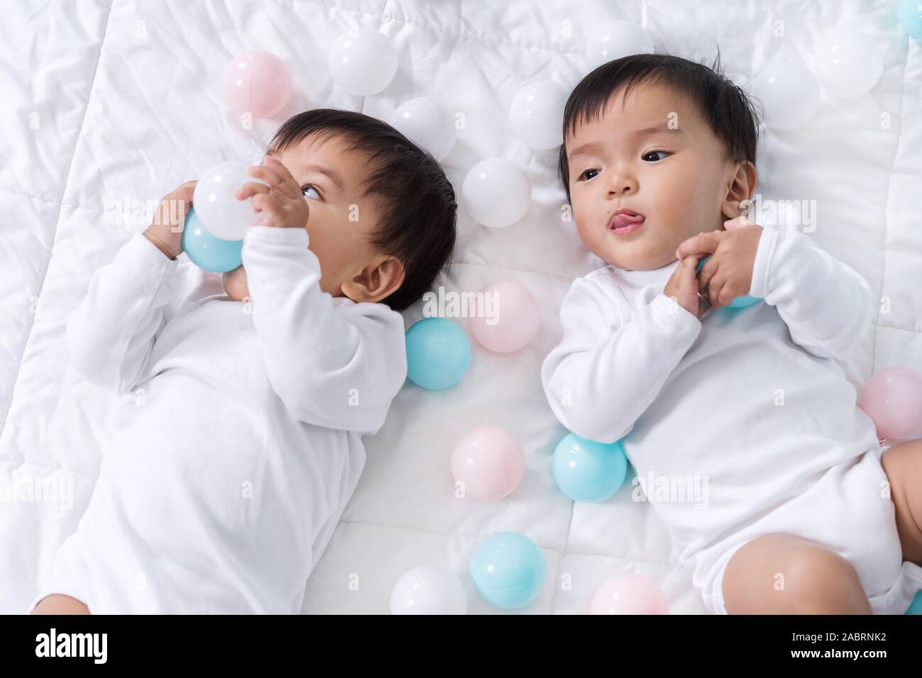 cheerful twin babies playing color ball on a bed Stock Photo - Alamy