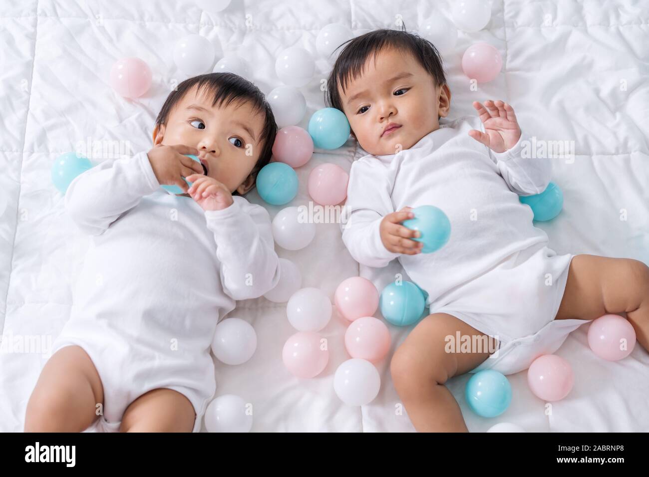 cheerful twin babies playing color ball on a bed Stock Photo - Alamy