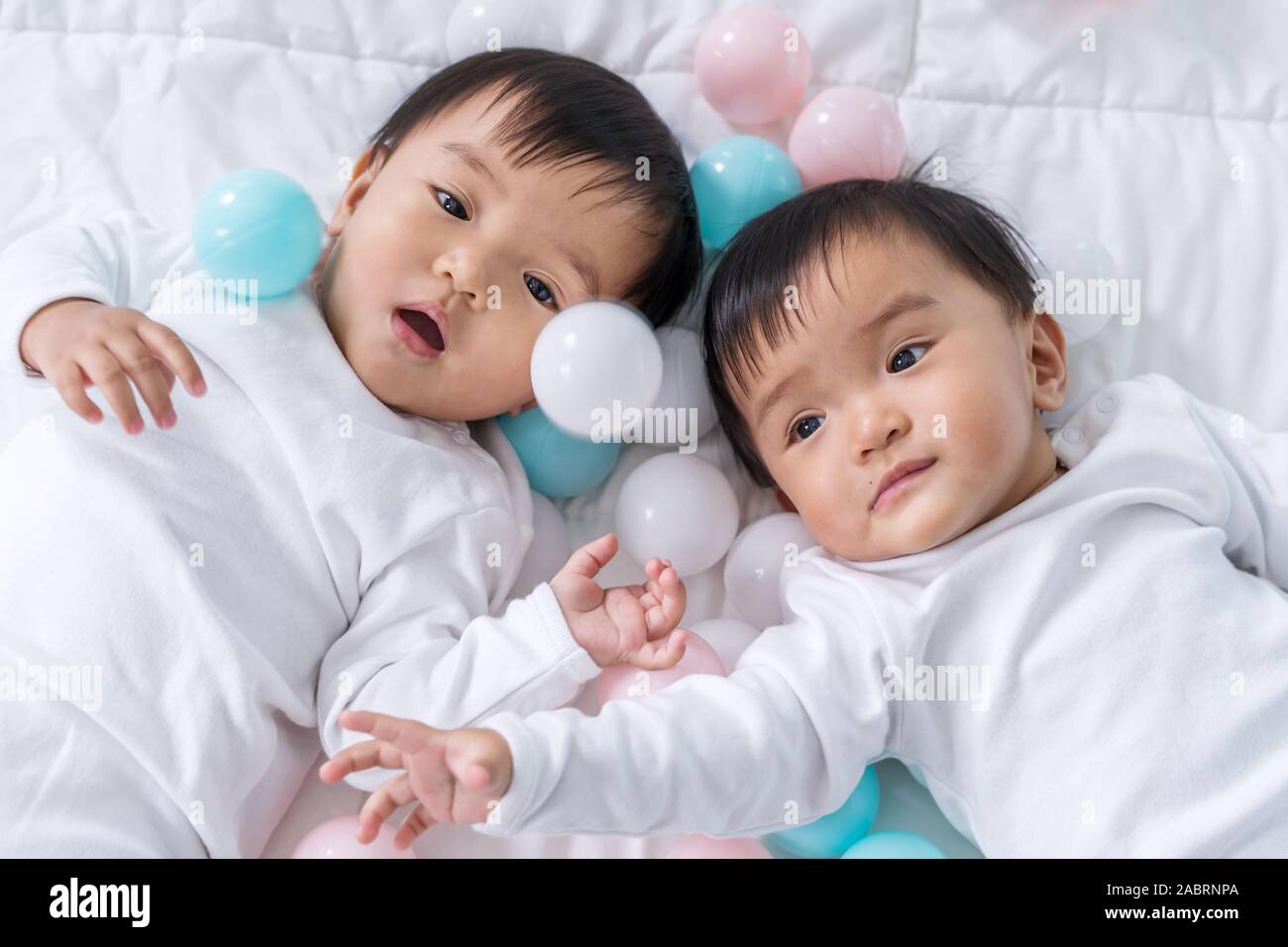 cheerful twin babies playing color ball on a bed Stock Photo - Alamy