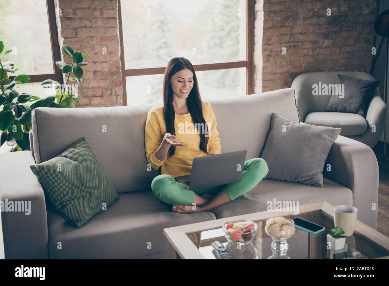 Full Length Photo Of Positive Cheerful Girl Sit Divan Cross Legs Use