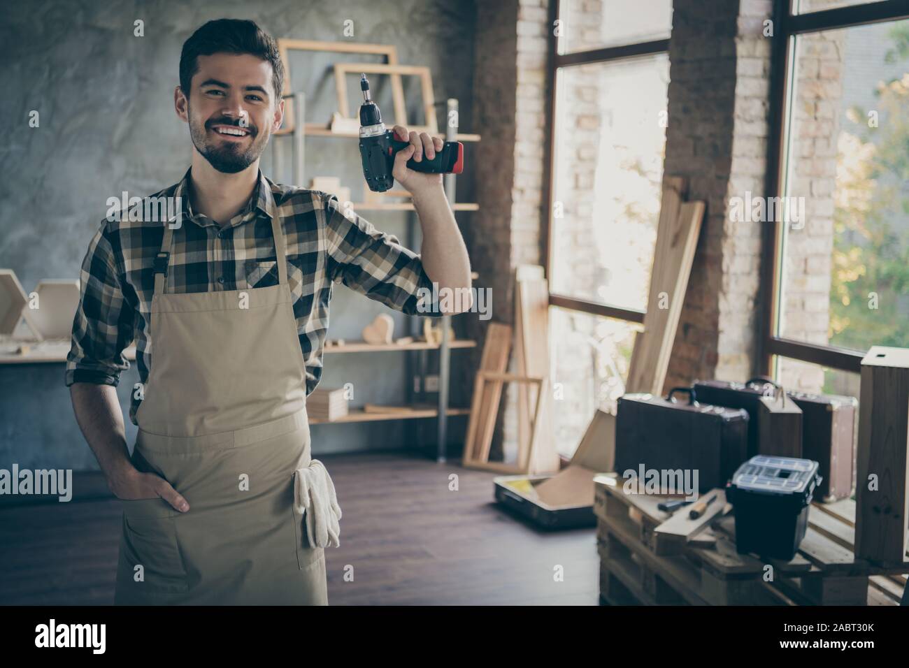 Photo of handsome confident guy master holding electric wireless drill ...