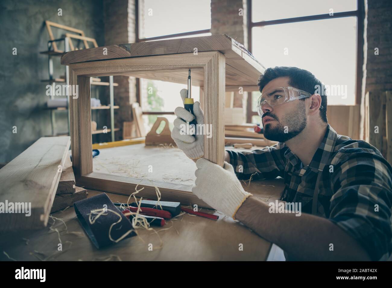 Focused workman in his house home garage repair wooden slab table use ...