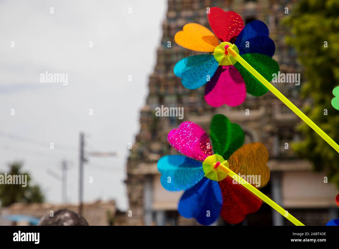colorful plastic windmill on yellow stick against Indian temple ...