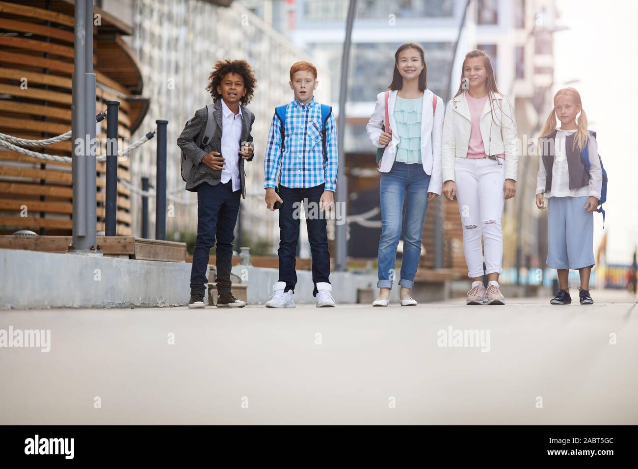 Group of multiethnic children walking together along the street in ...