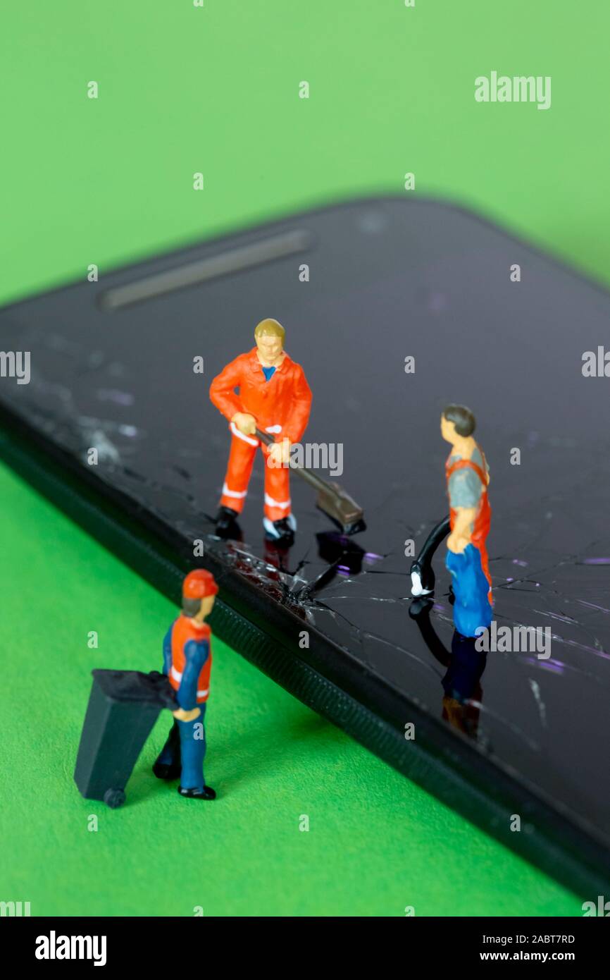 Miniature garbage man recycling and cleaning an broken smartphone with ...
