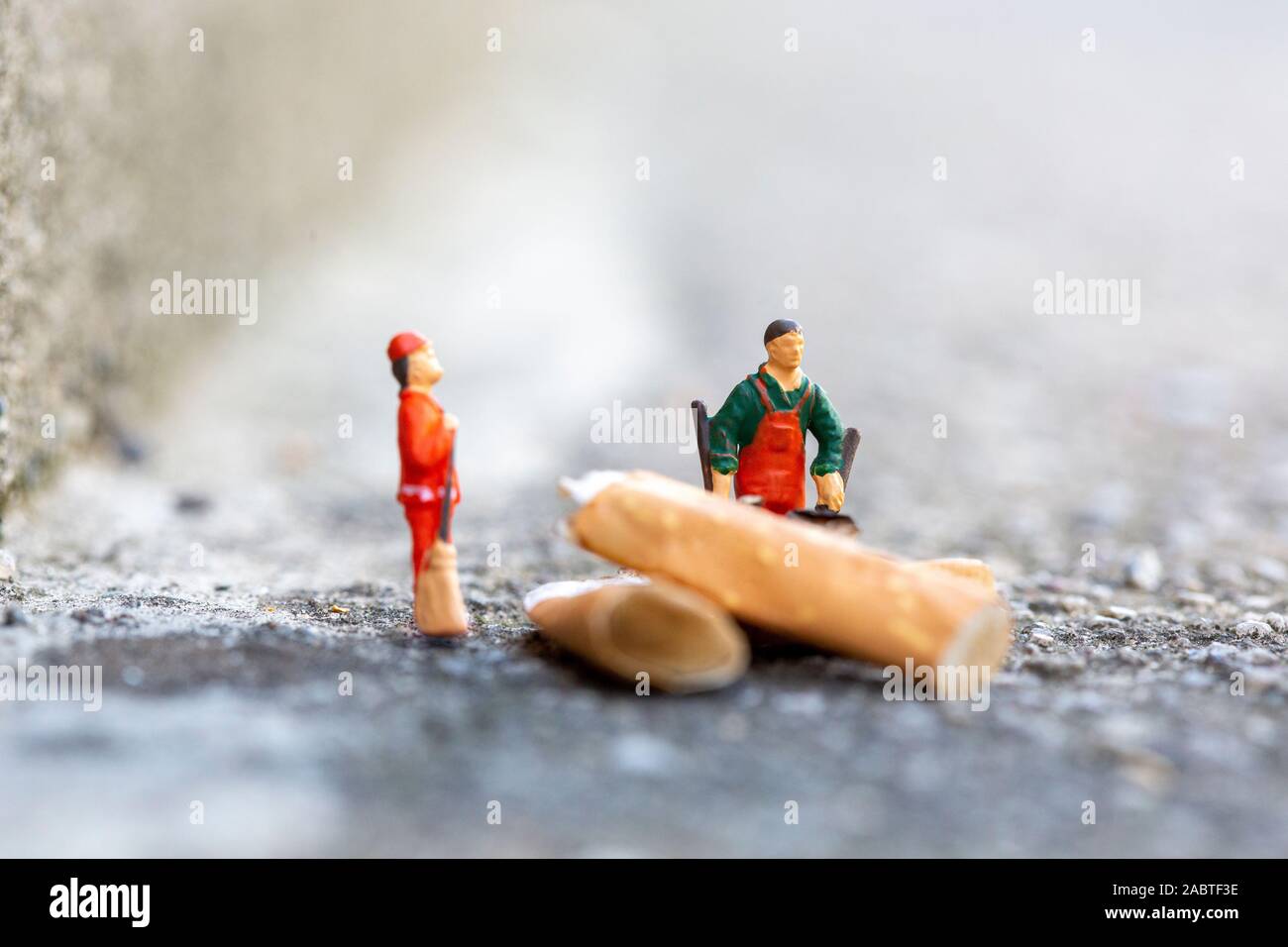 Two miniature garbage men cleaning and sweeping smoked cigarettes on ...