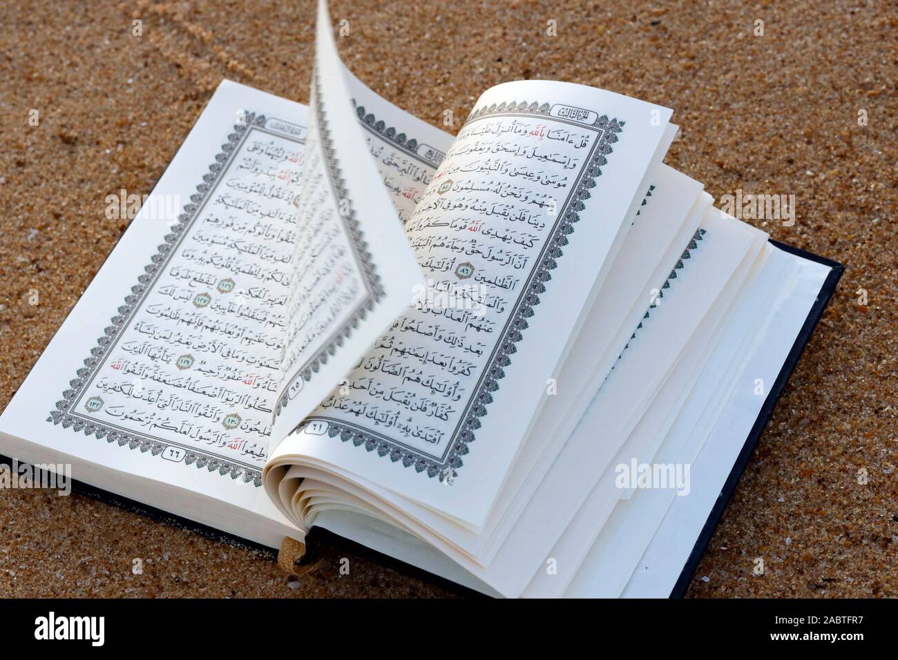 Open Quran on sand beach Stock Photo - Alamy