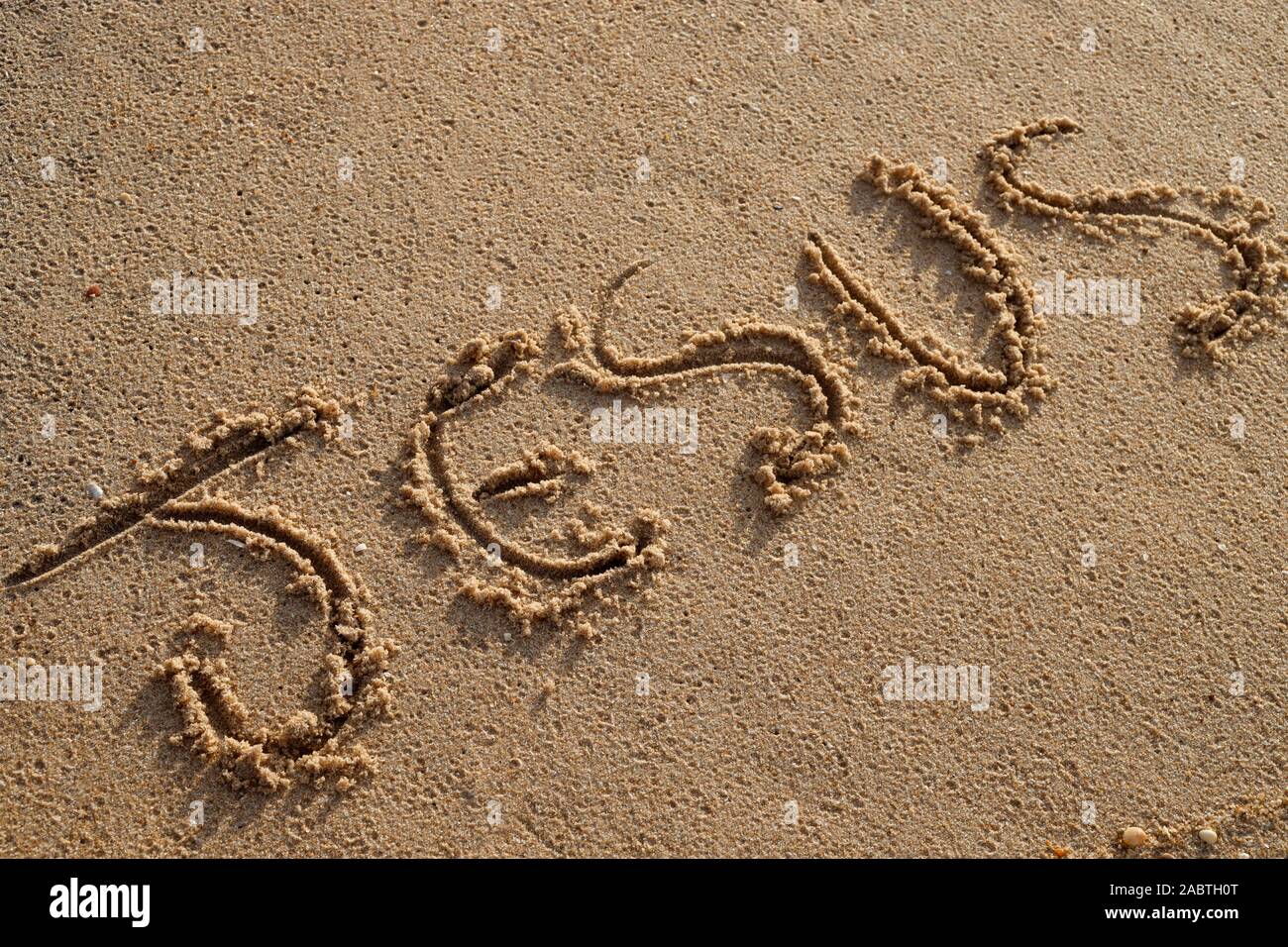 The name of Jesus written in wet sand on beach Stock Photo - Alamy