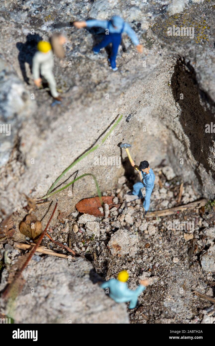Miniature worker with a hammer working in a quarry while an instructor ...