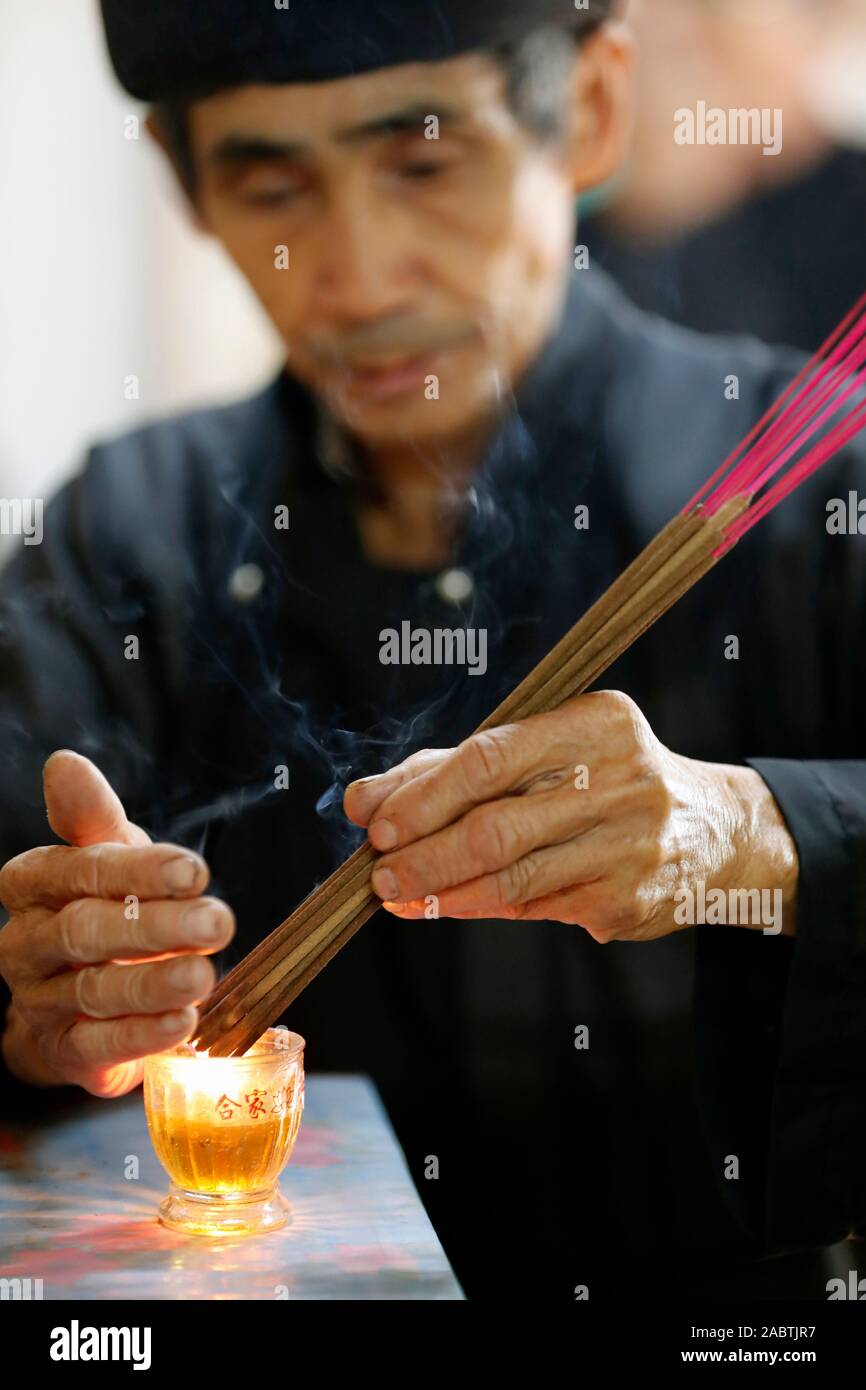 Ceremony in a buddhist chinese temple. Man praying with burning incense ...
