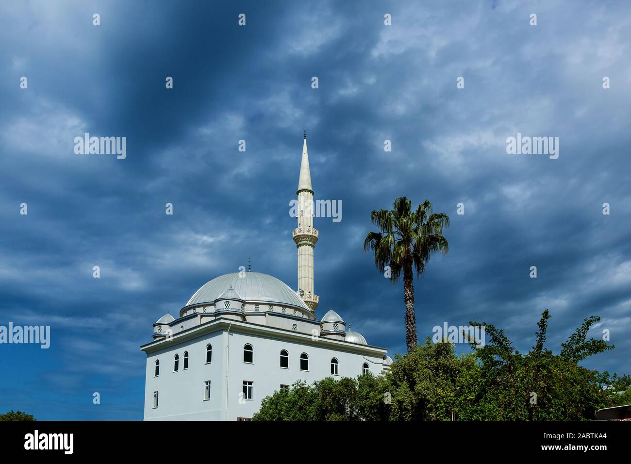 Turkish landscape with white mosque and minaret on a dark blue cloudy ...
