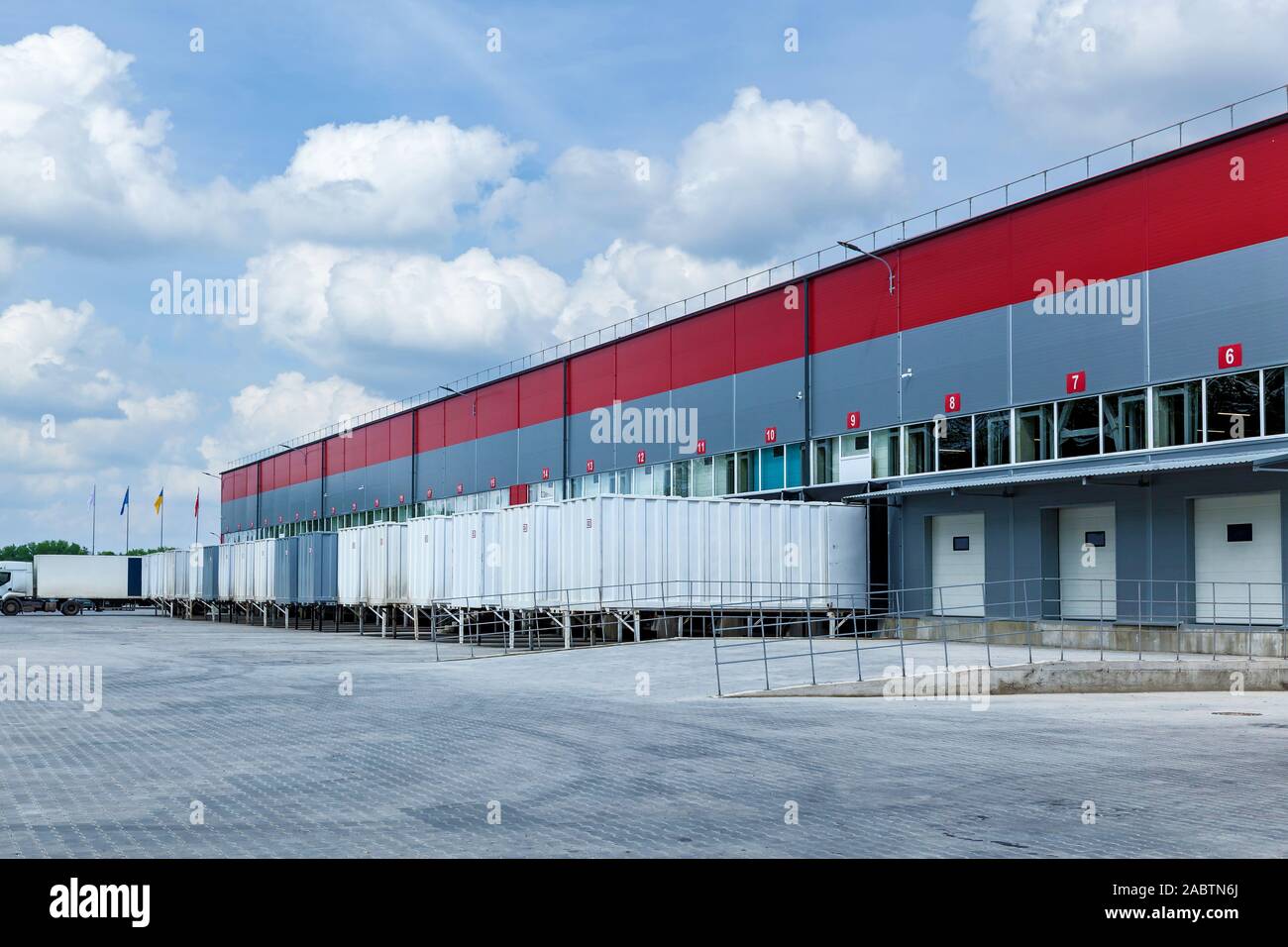 A modern truck of white color leaves the warehouse gate with some goods ...