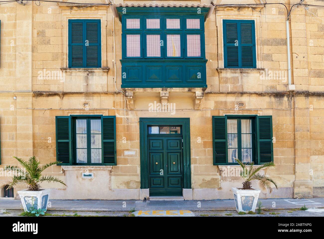 Malta architecture, facade of a house with wooden windows and a green ...