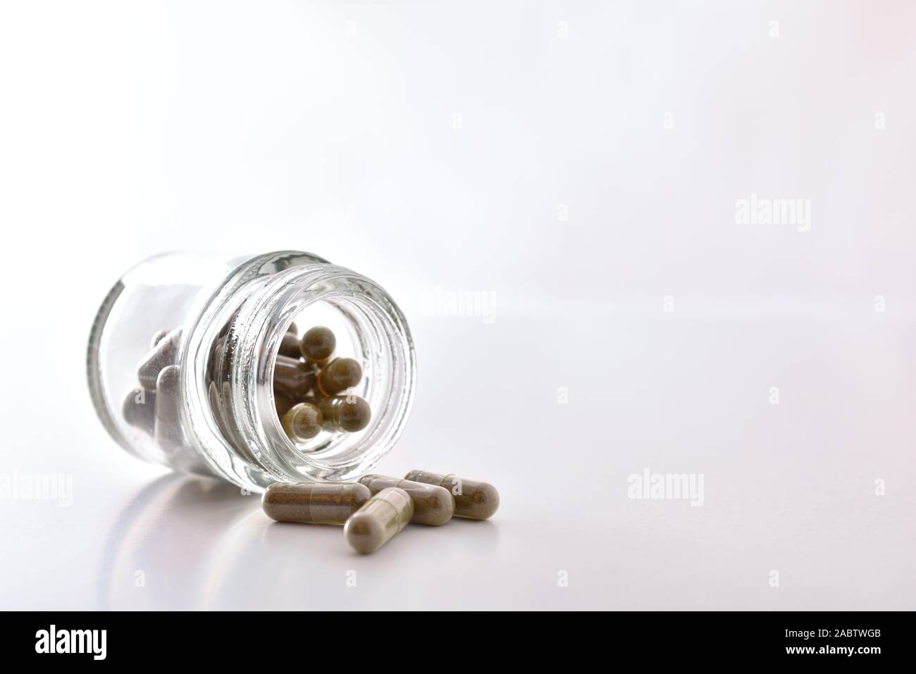 Glass jar filled with medication capsules on white table and isolated ...
