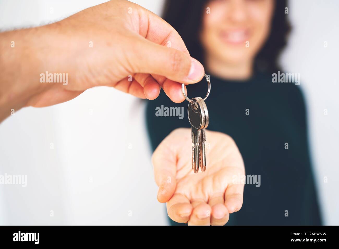 Young lady taking keys from female real estate agent during meeting ...