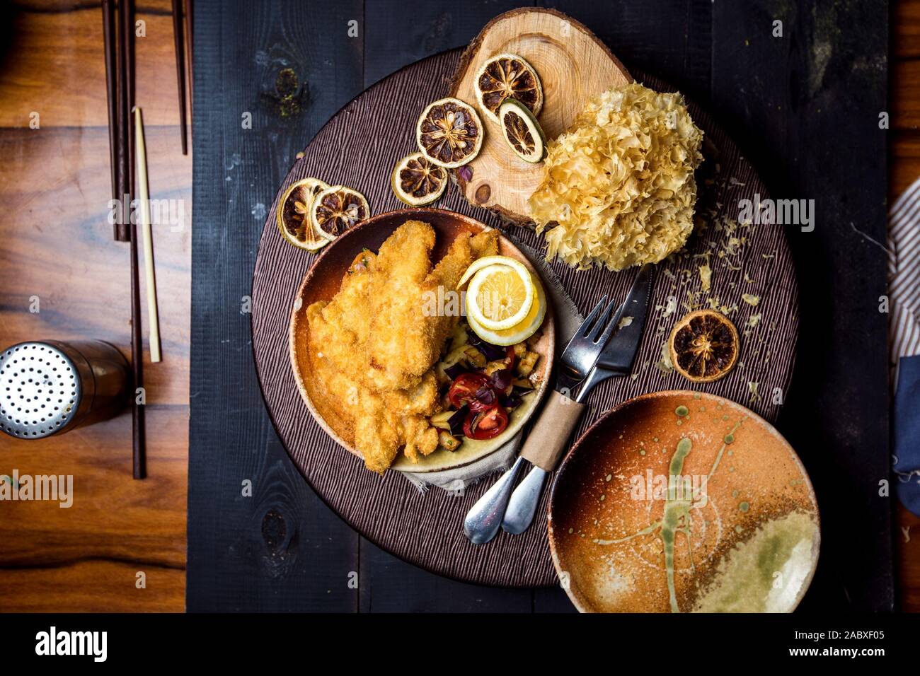top view of crispy fried fish served with lemon, fries and vegetable ...