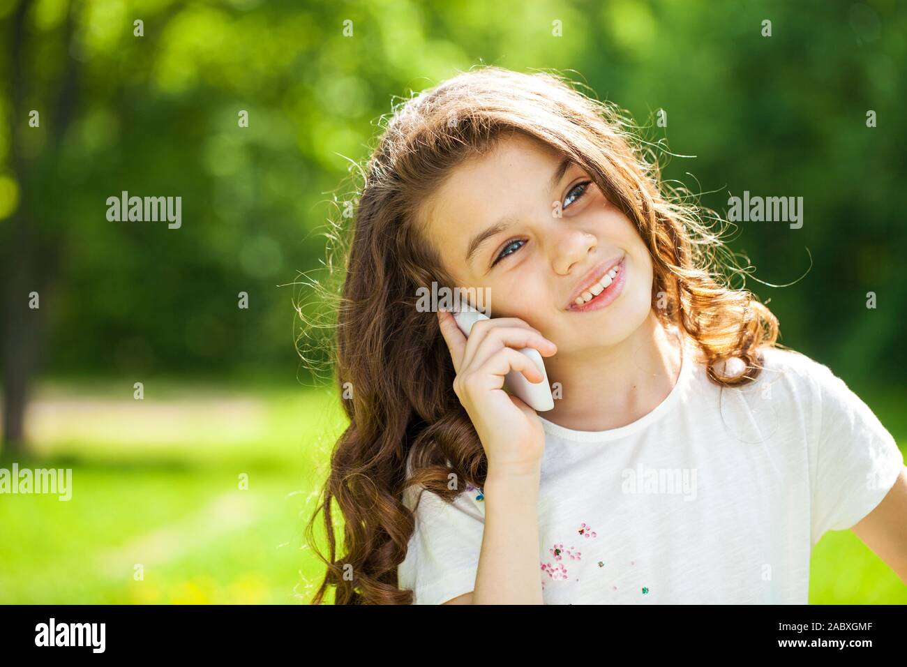 Beautiful little girl calling by mobile phone on the background of ...