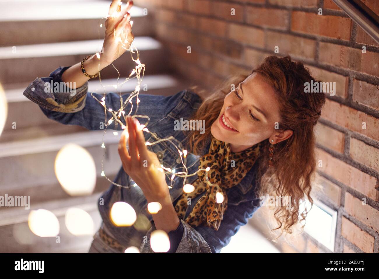 Happy redhead Caucasian woman playing with fairy lights outdoors Stock ...