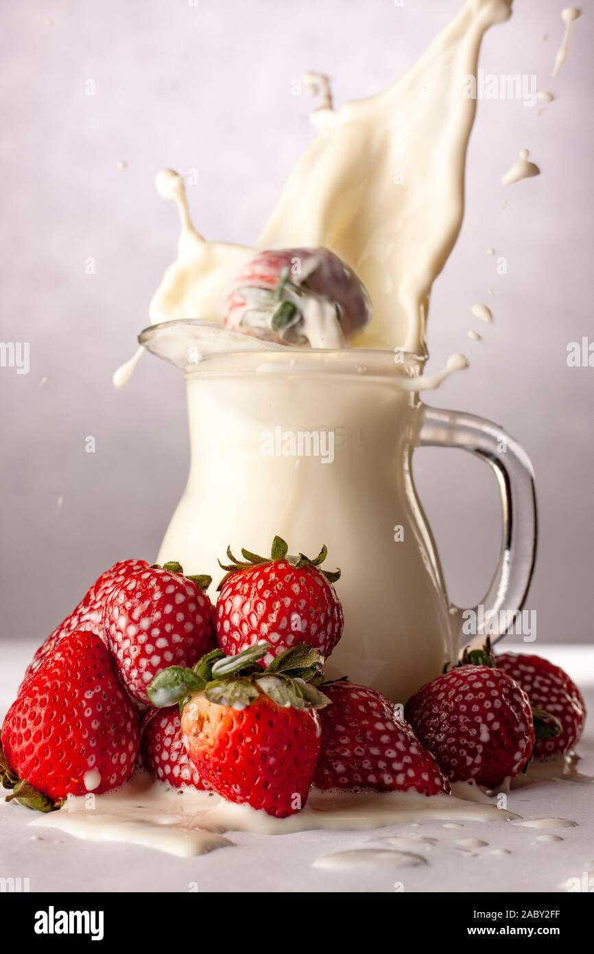 splash strawberry over milk/cream w/ assortment of straberries on ...