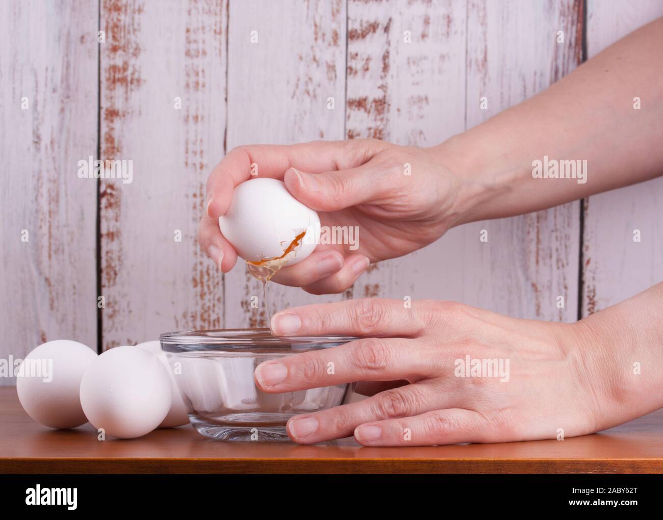 Female hand broking a white raw eggs as ingredient ready to cook Stock ...
