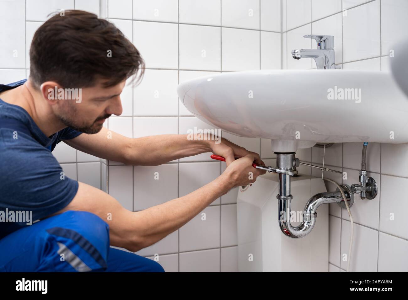 Young Plumber Fixing A Sink In Bathroom Stock Photo - Alamy