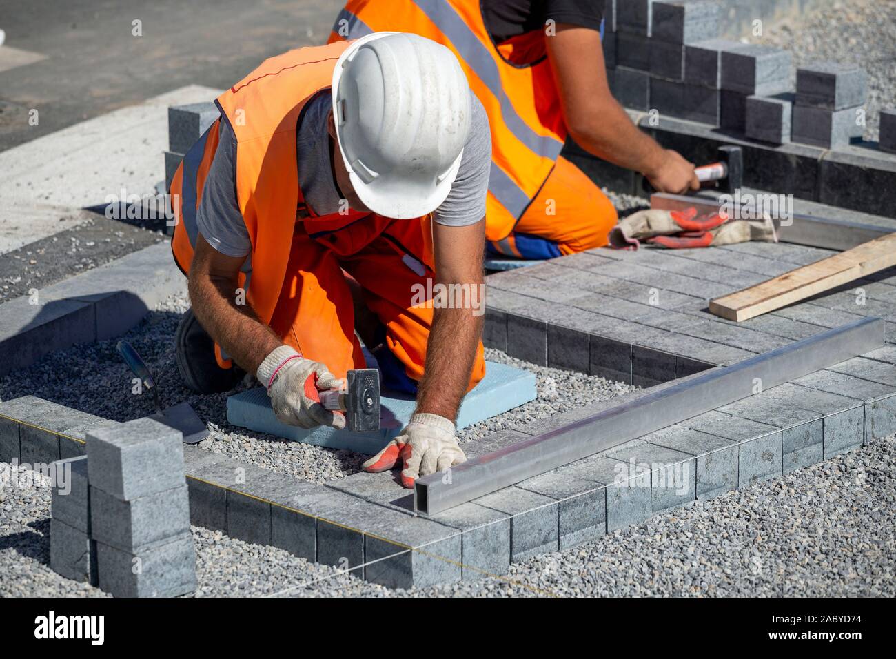 Construction workers laying paving bricks outdoor on a prepared base ...