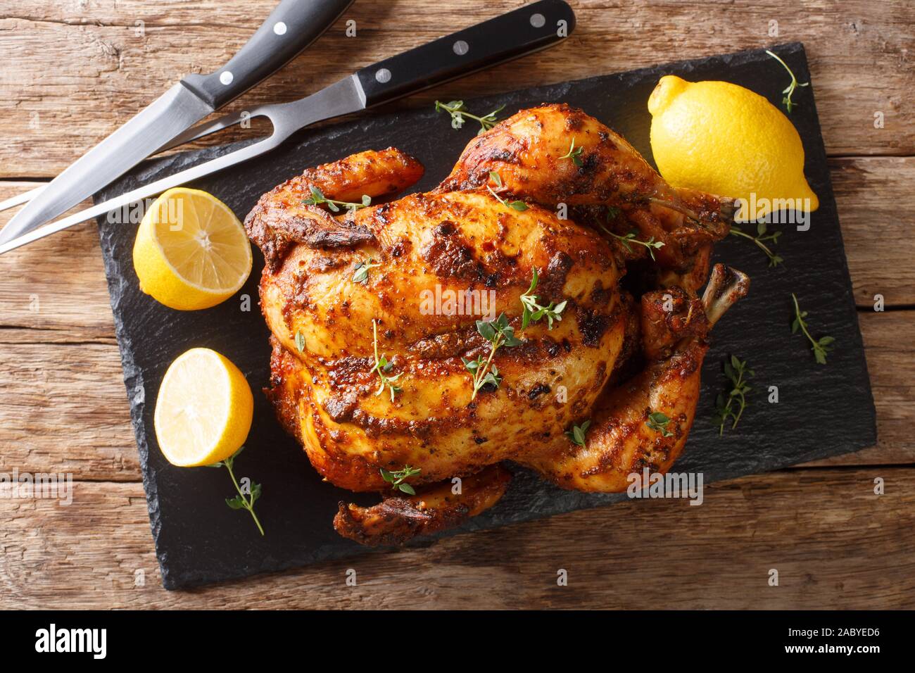 Homemade chicken rotisserie with thyme, lemon closeup on a slate board ...