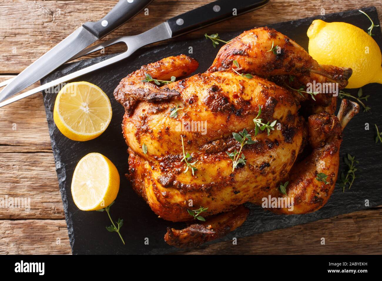 Crispy juicy rotisserie chicken close-up on a slate board on the table ...
