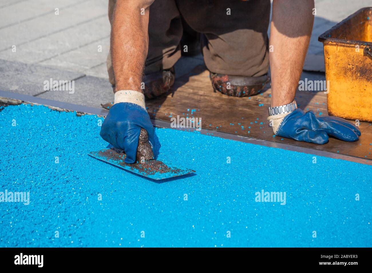 Leveling rubber coating with trowels, mason hands spreading rubber ...