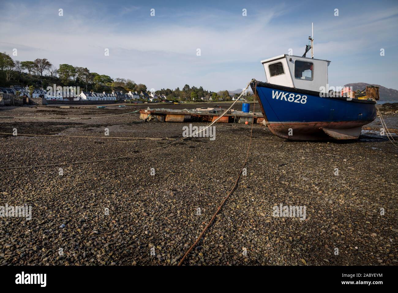 A fishing boat lies stranded at its mooring on the mudflats of the ...