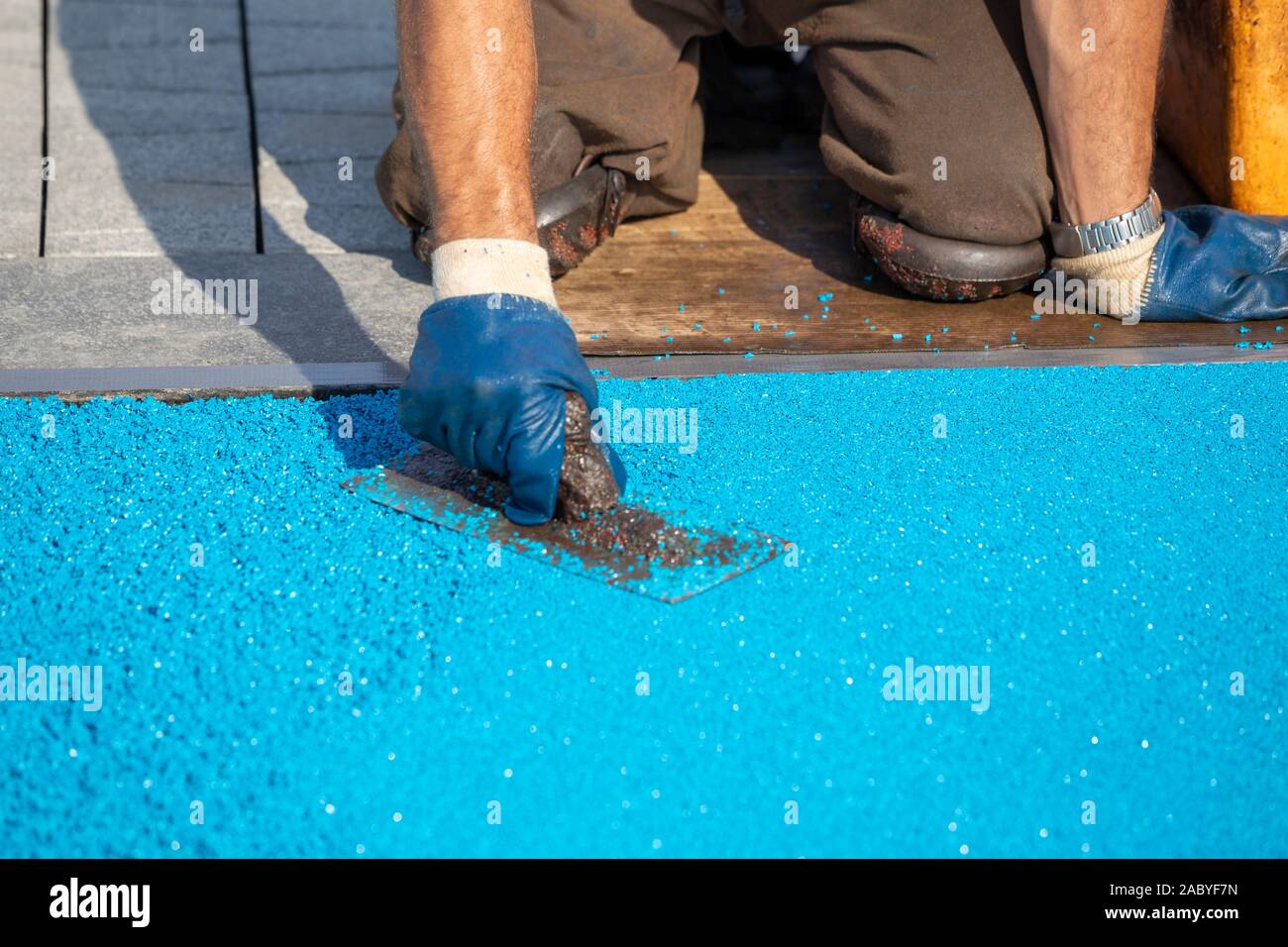 Mason leveling rubber coating for playgrounds with trowel, mason hand ...
