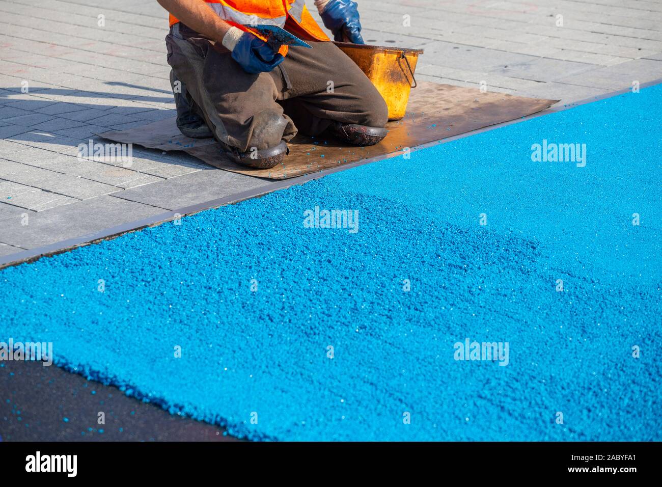 Mason spreading rubber coating for playgrounds applied on the surface ...