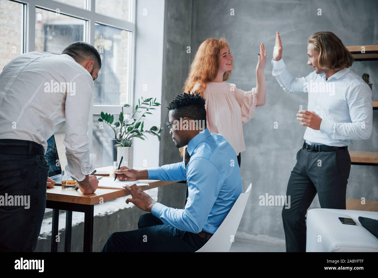 High five at background. Office workers loaded with work and writing ...
