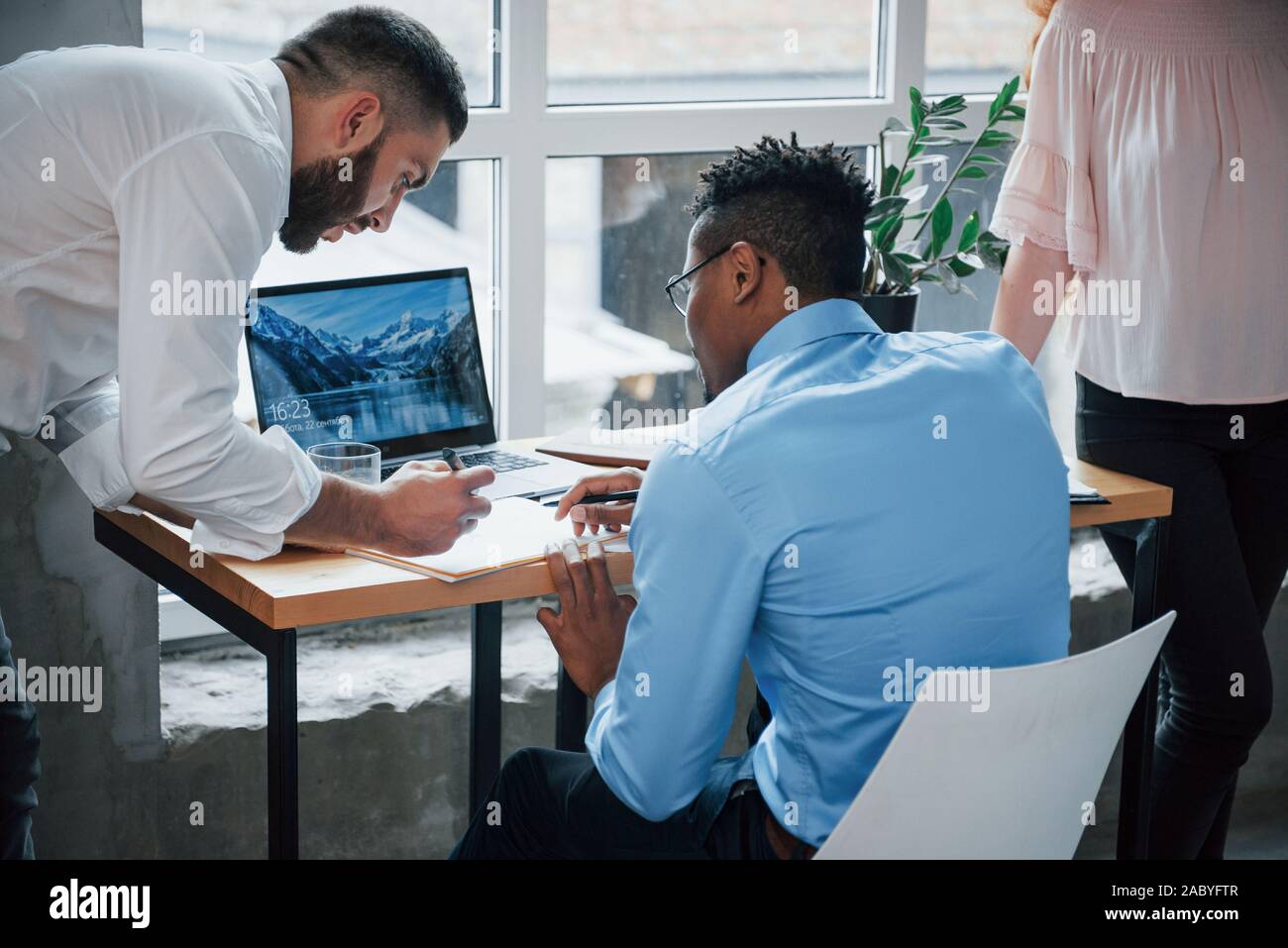 Back view. Office workers loaded with work and writing routine reports ...