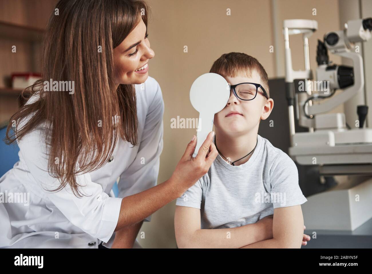Sight test in clinic. Female doctor covers kid eye with medical tool ...