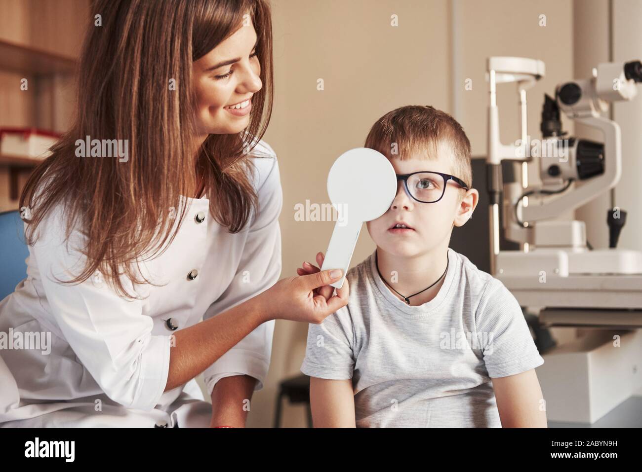 Now tell me what you see. Female doctor covers kid eye with medical ...