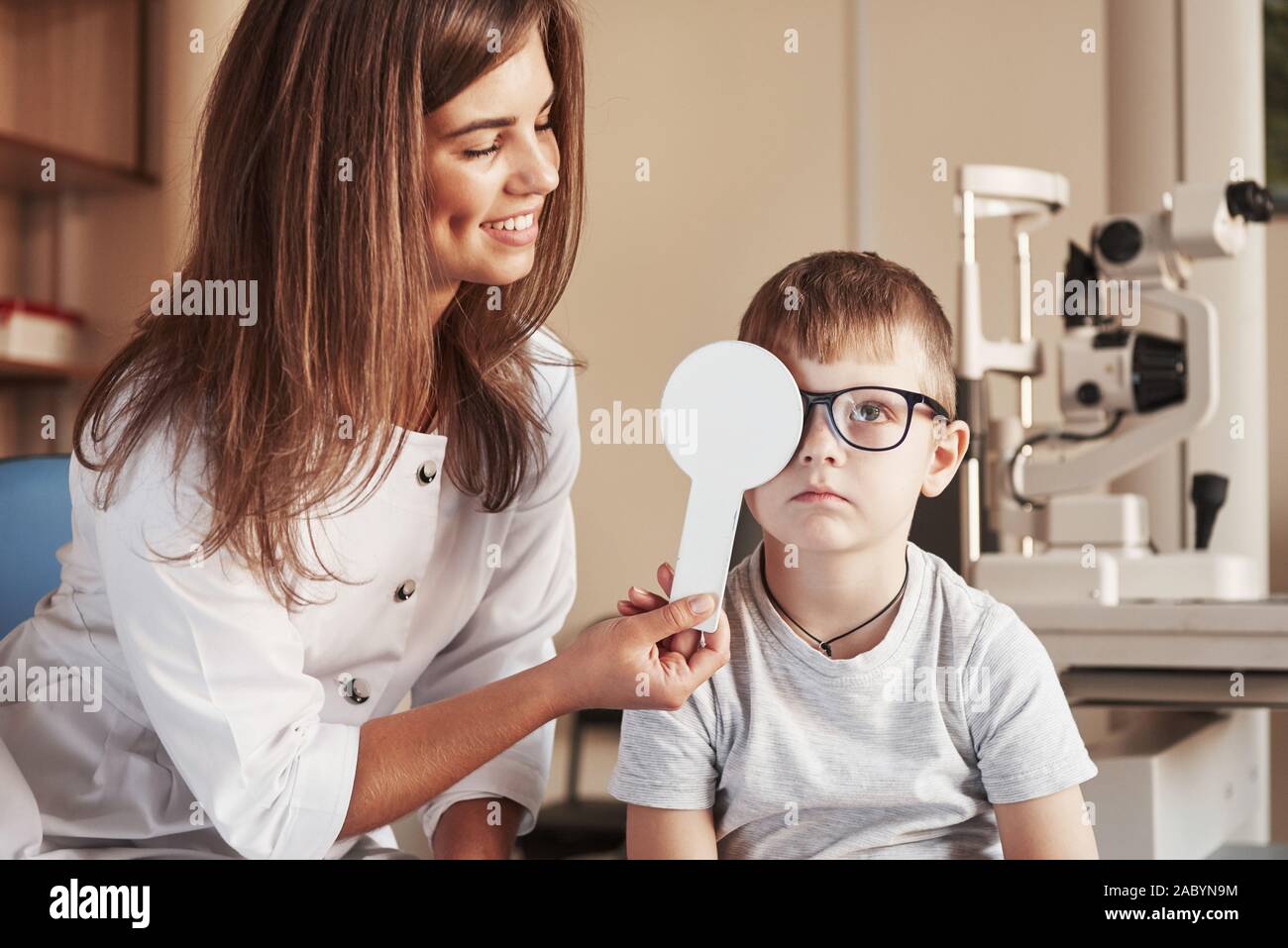 Female doctor covers kid eye with medical tool for checking visual ...